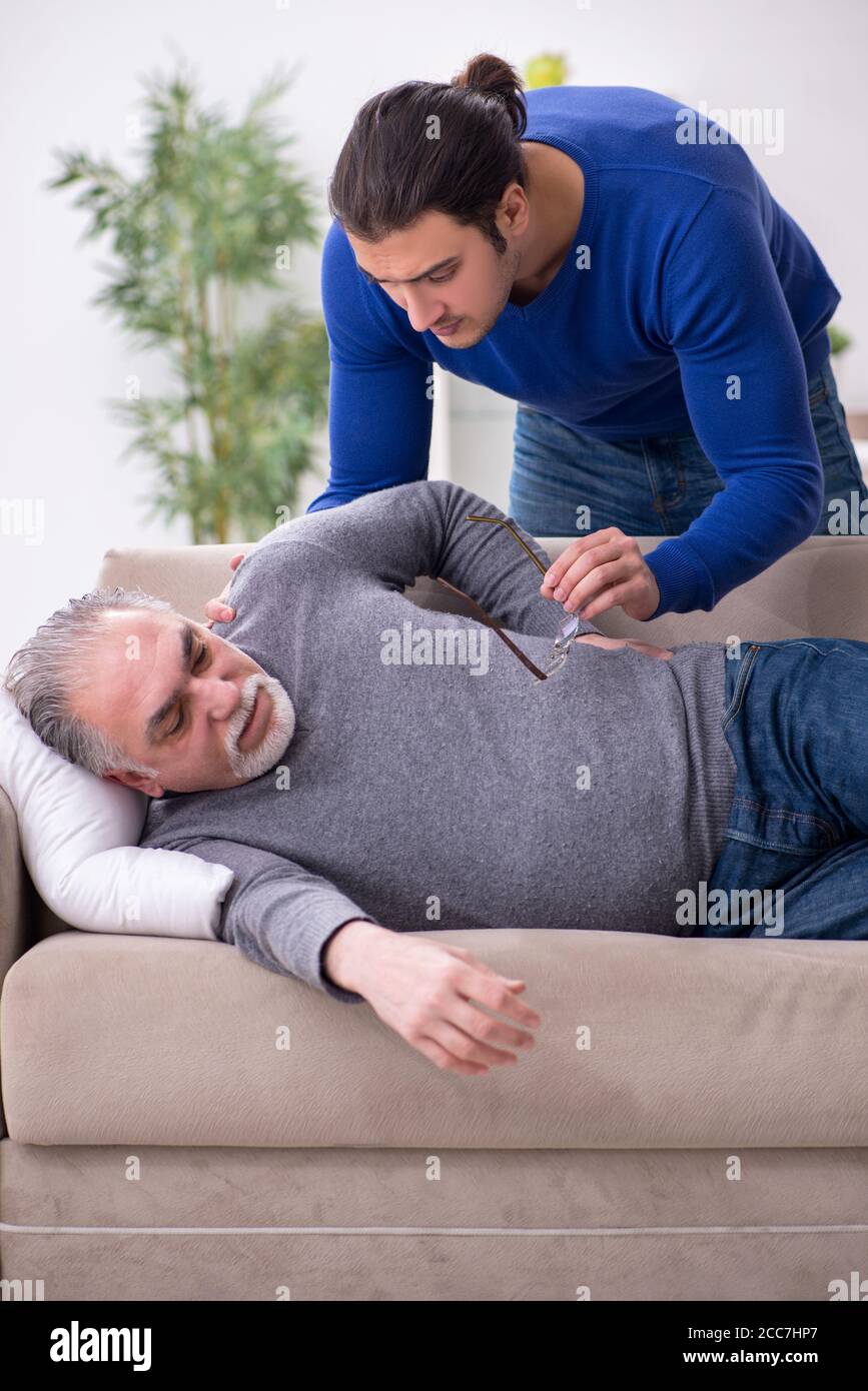 Young man looking after his sick father at home Stock Photo - Alamy