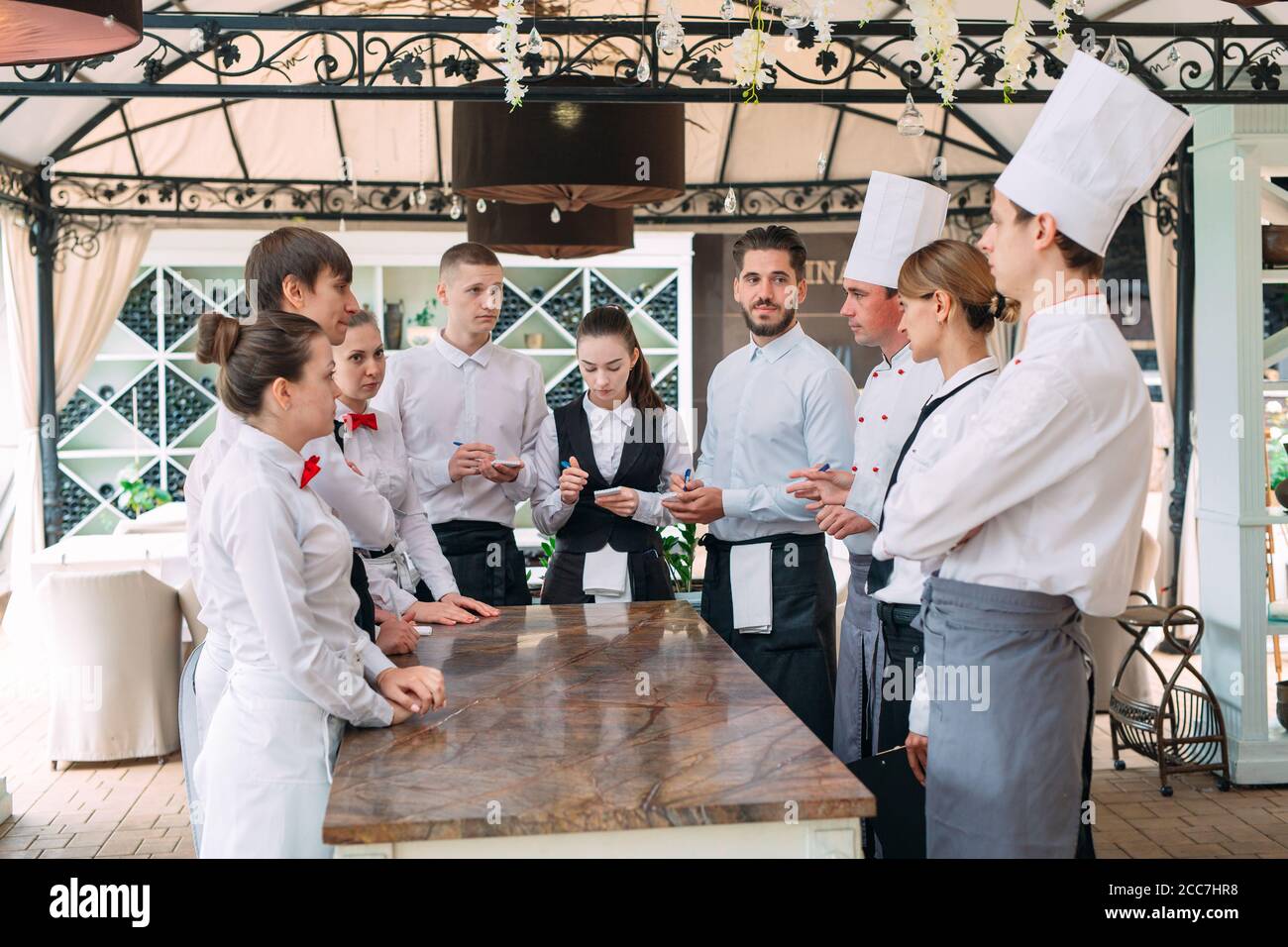 Restaurant manager and his staff in terrace. interacting to head chef ...