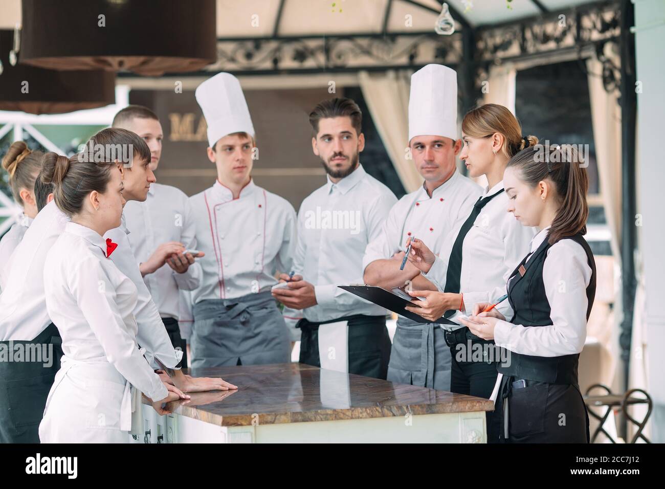 Restaurant manager and his staff in terrace. interacting to head chef ...