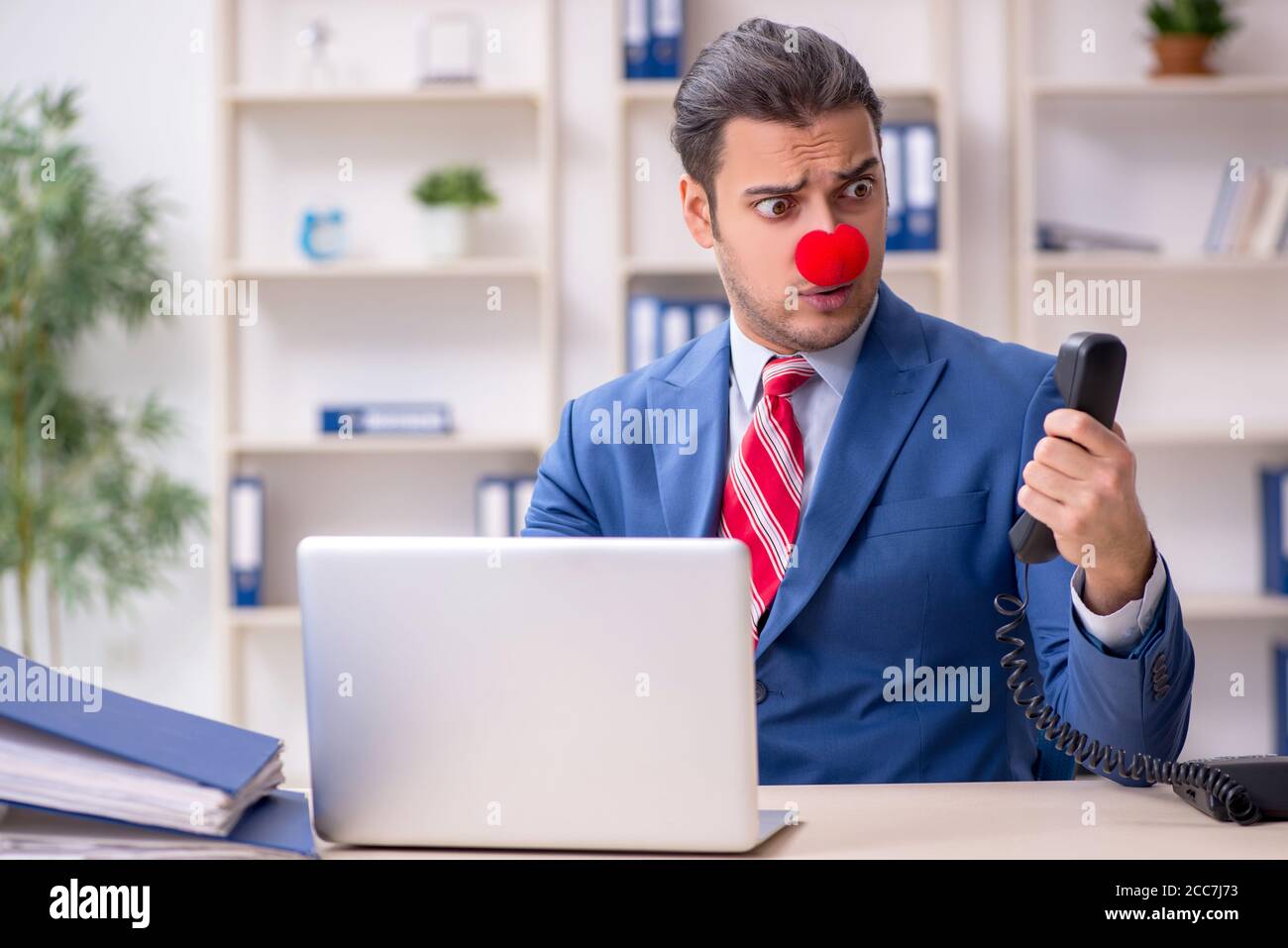 Funny employee clown working in the office room Stock Photo - Alamy