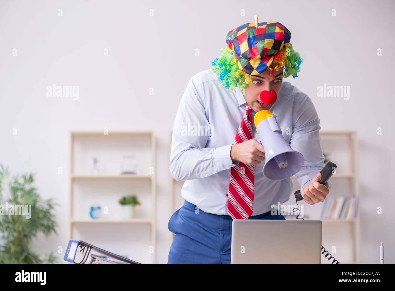 Funny employee clown working in the office room Stock Photo - Alamy