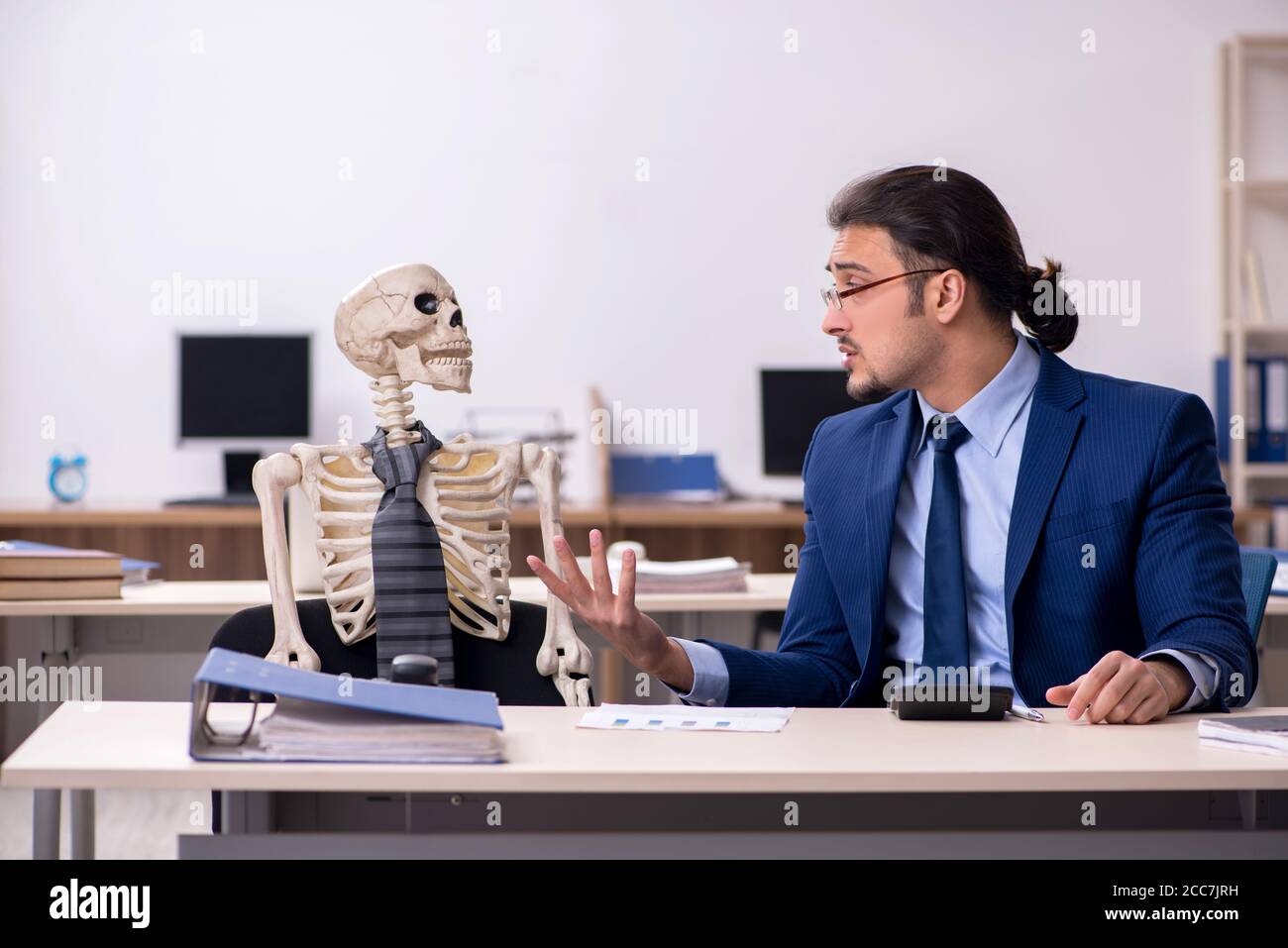Young employee with skeletons in the office Stock Photo - Alamy