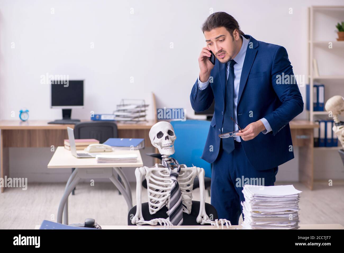 Young employee with skeletons in the office Stock Photo - Alamy