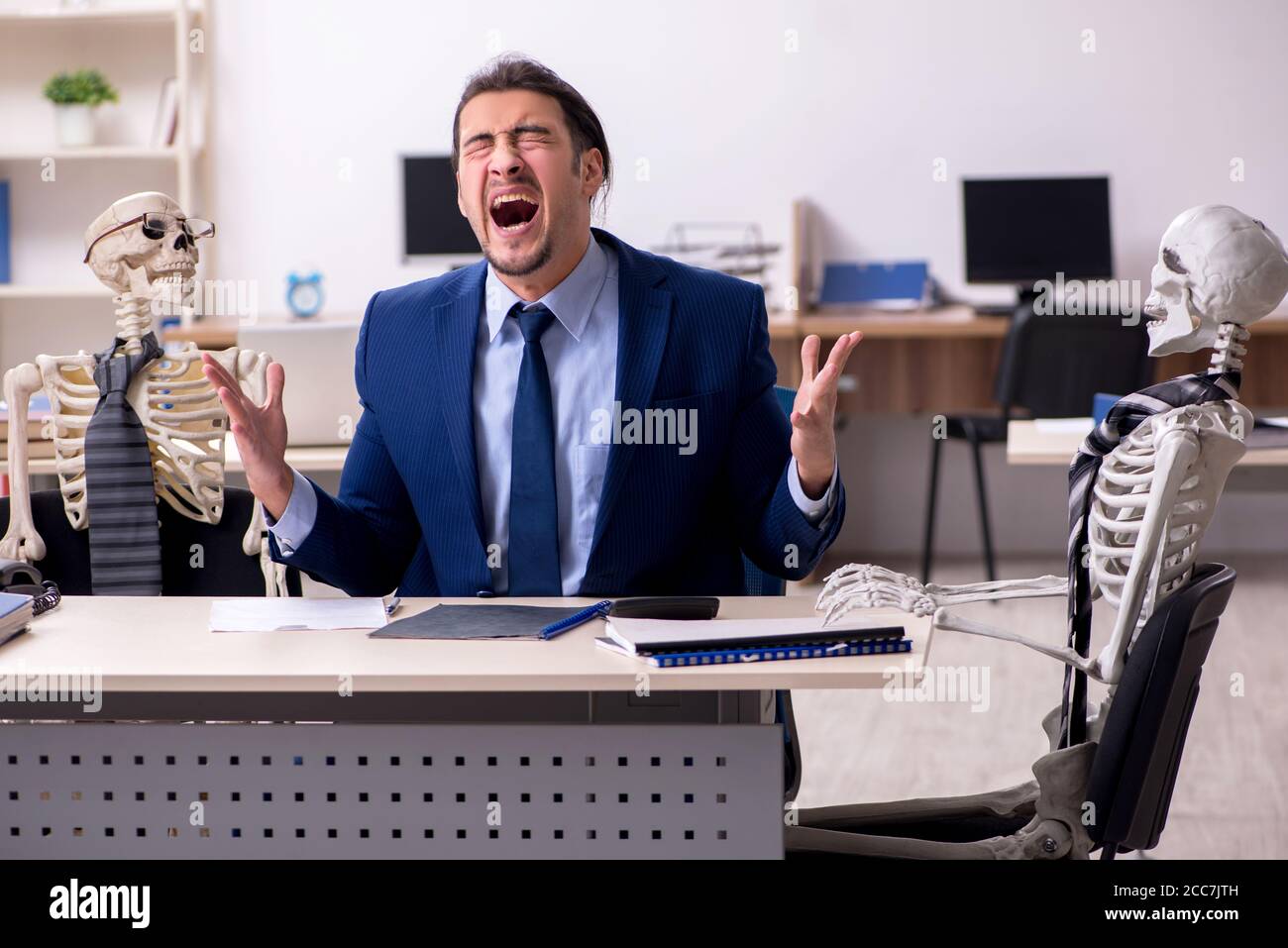 Young employee with skeletons in the office Stock Photo - Alamy