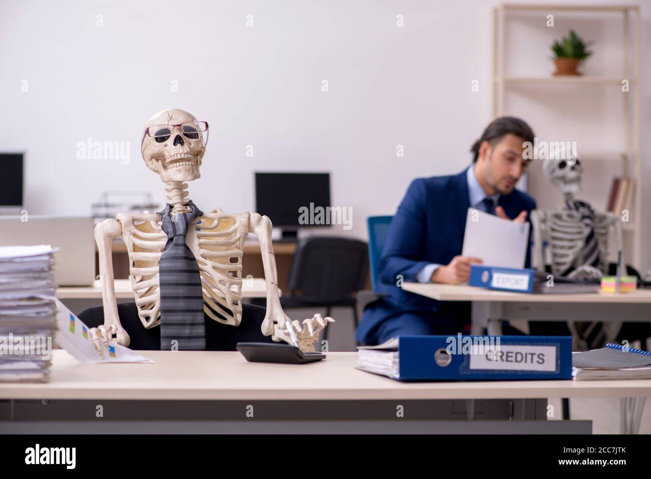 Young employee with skeletons in the office Stock Photo - Alamy