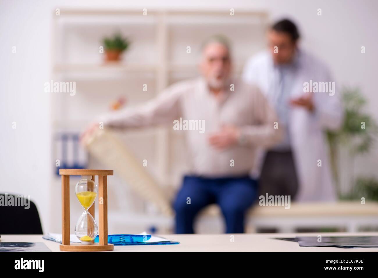 Old male patient visiting young doctor in time management concept Stock ...