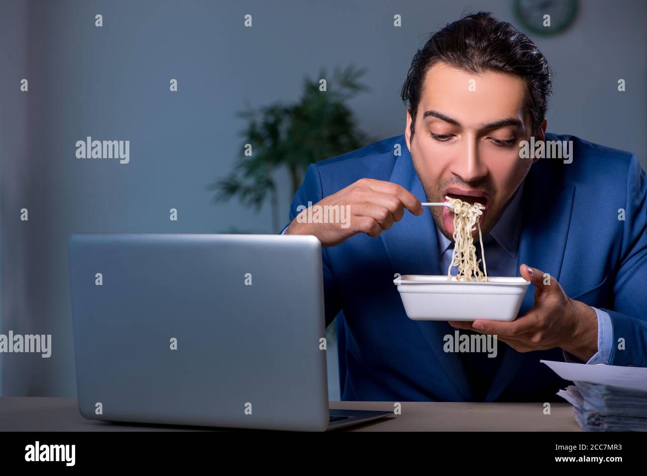 Hungry employee working late in office Stock Photo - Alamy