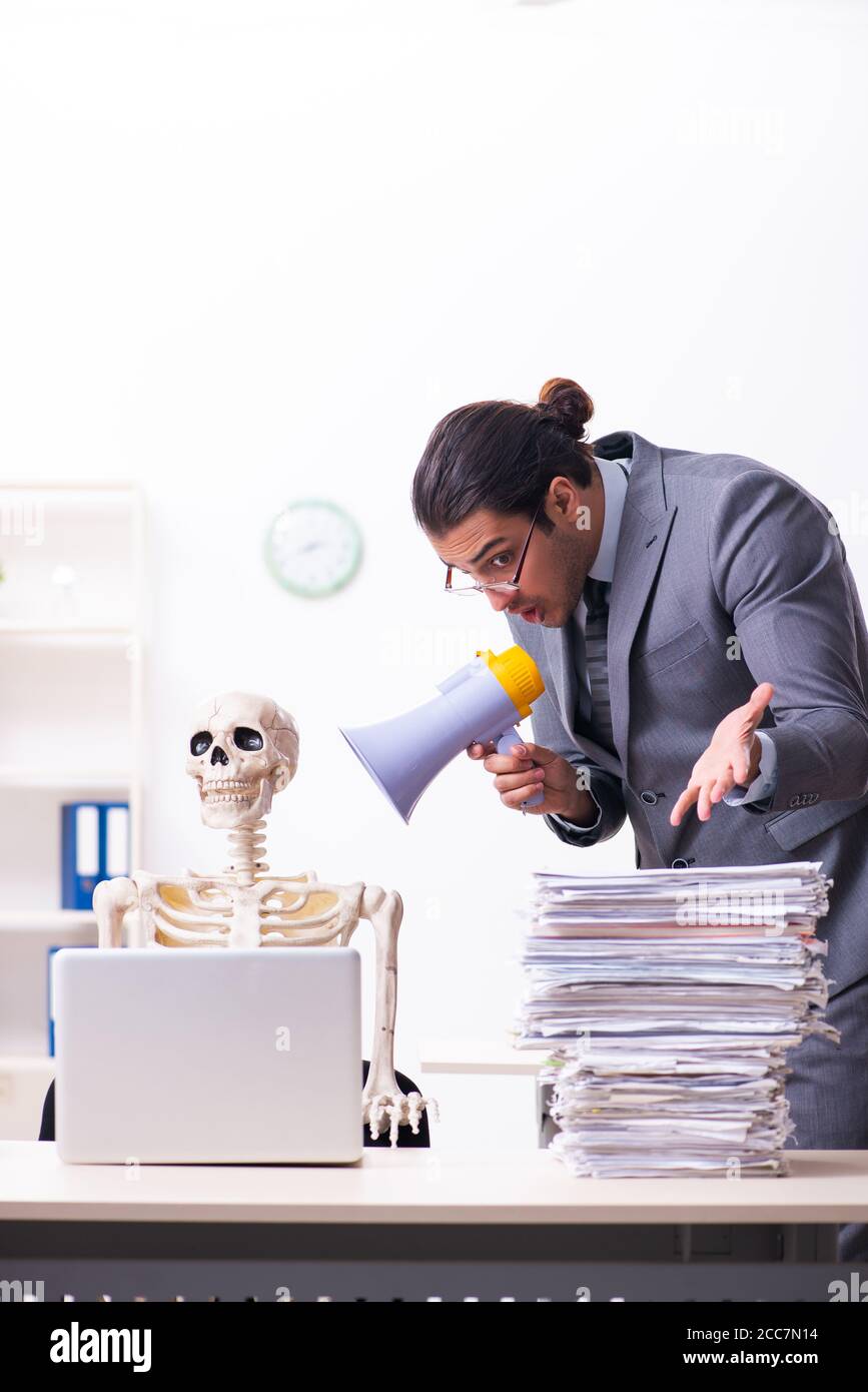 Young employee and skeleton in the office Stock Photo - Alamy