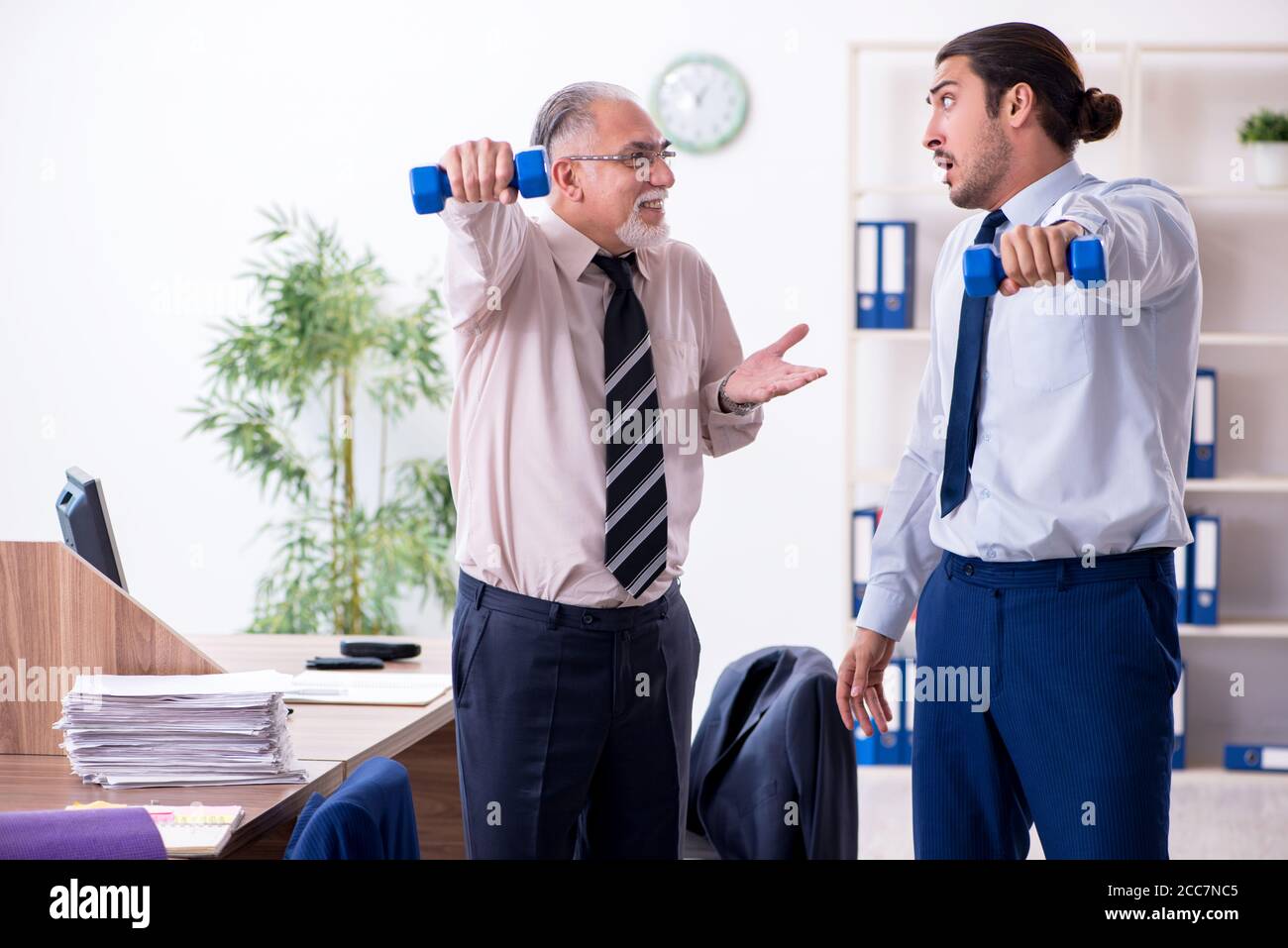 Two employees doing physical exercises at the workplace Stock Photo - Alamy