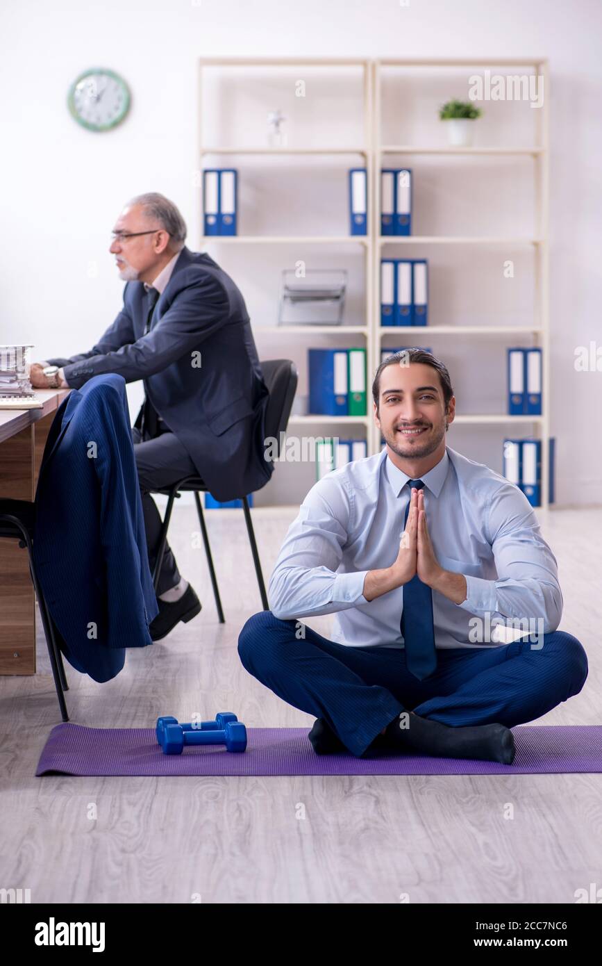 Two employees doing physical exercises at the workplace Stock Photo - Alamy