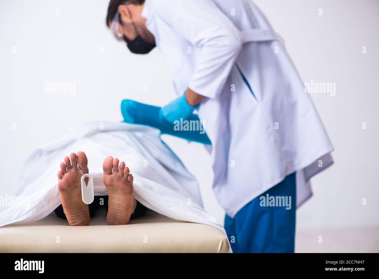 Police coroner examining dead body in morgue Stock Photo - Alamy