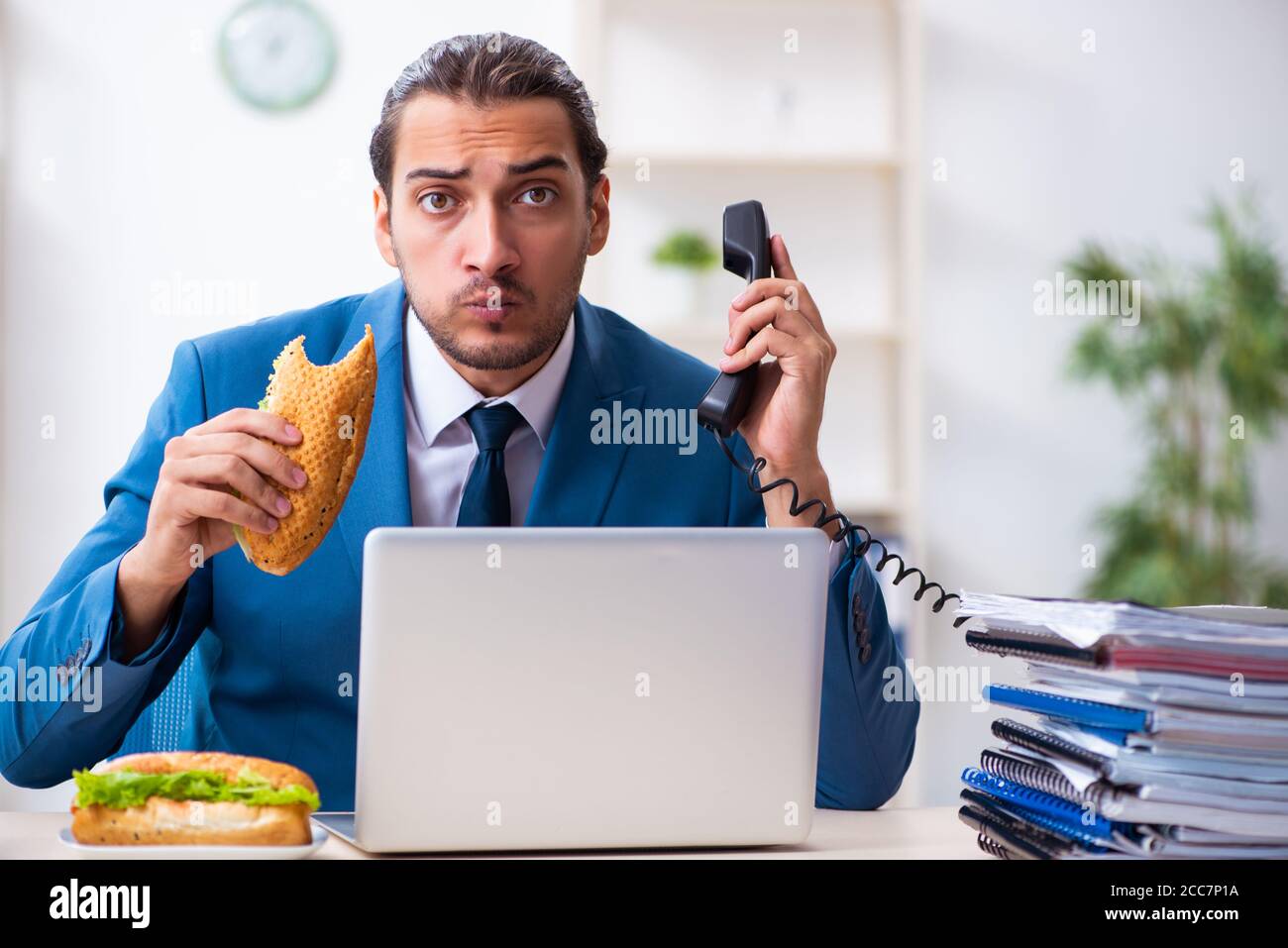 Young employee having breakfast at workplace Stock Photo - Alamy