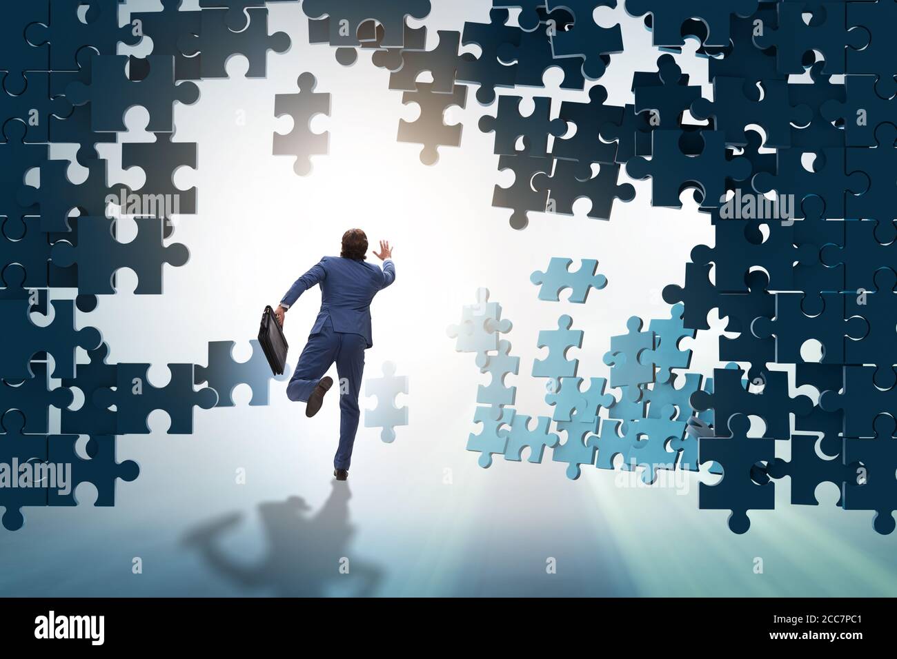 Businessman breaking wall of jigsaw puzzle Stock Photo - Alamy