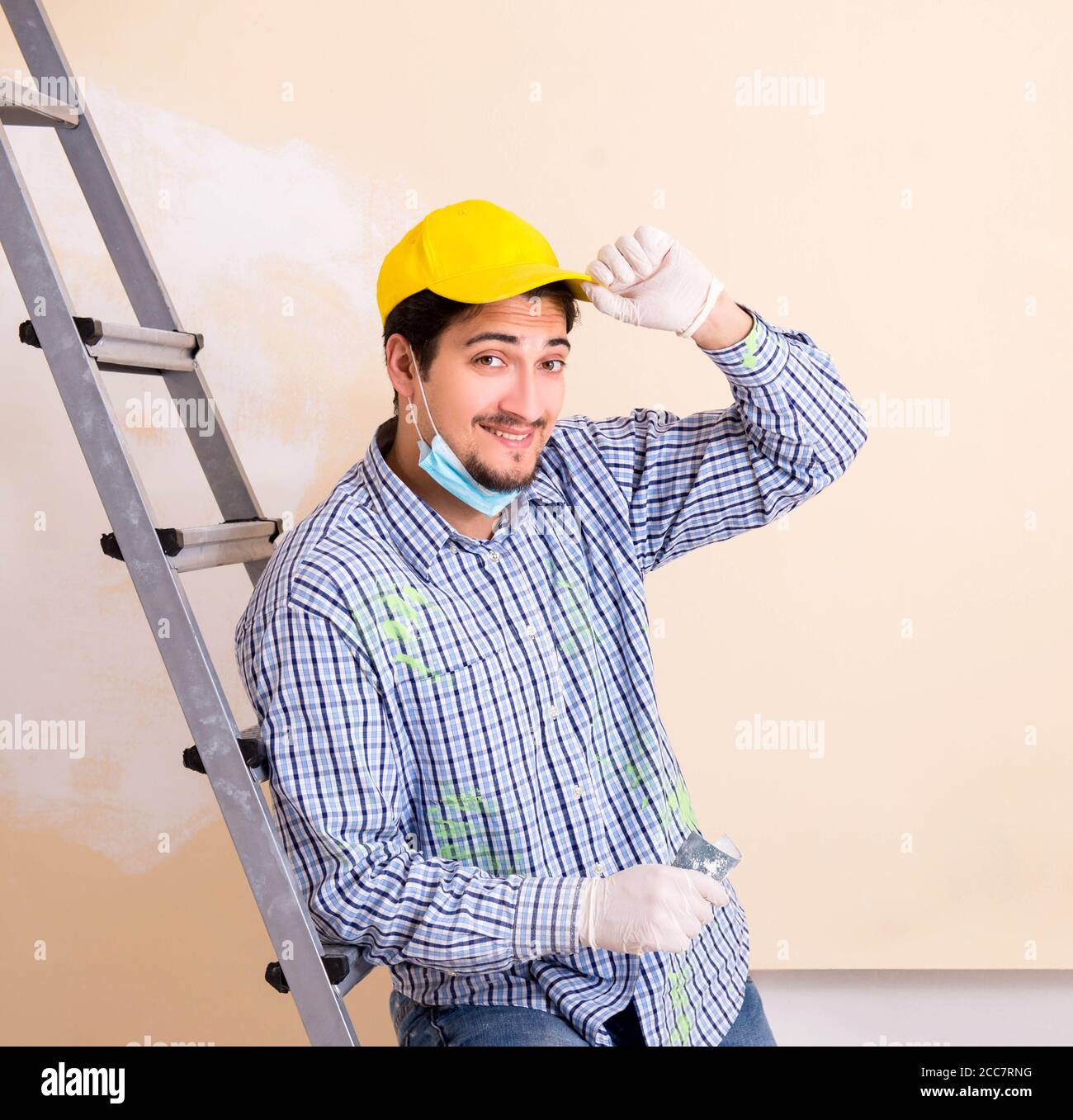 The young contractor sanding wall down with sandpaper Stock Photo - Alamy