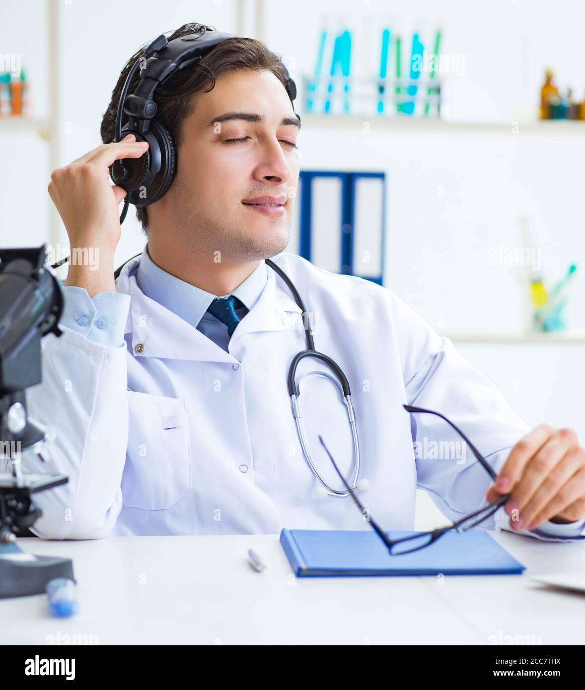 Happy excited doctor listening to music during lunch break in hospital ...