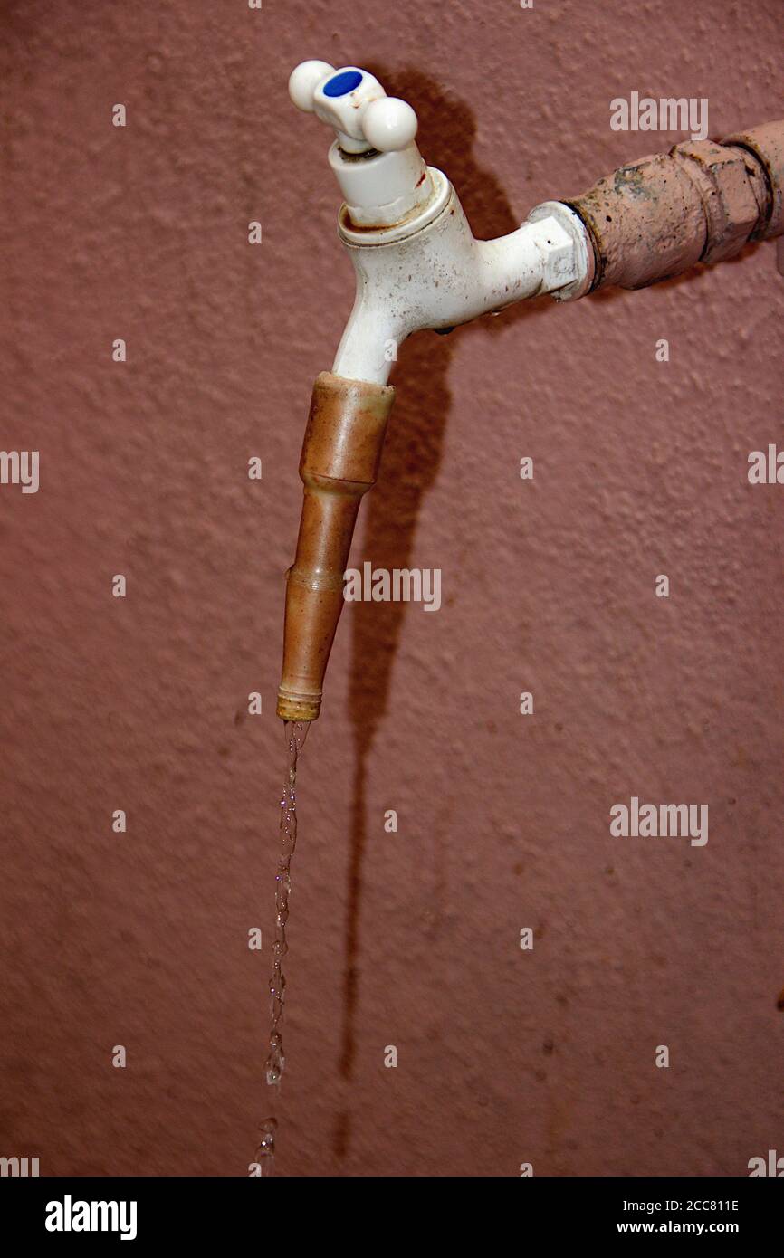 View of flow of water through nozzle of tap against brown background ...