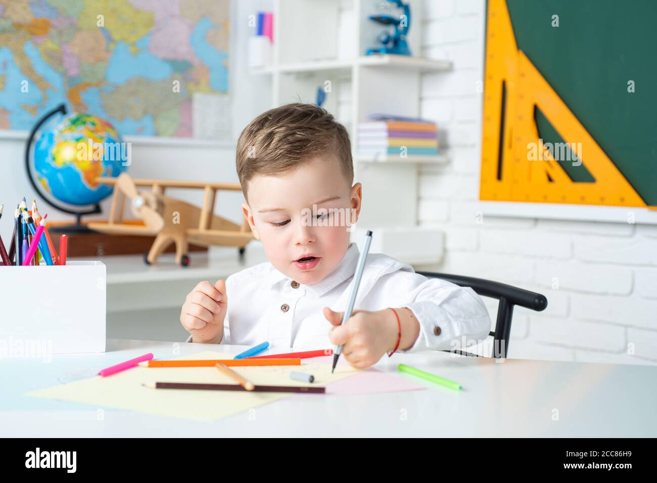 Kid boy writing in classroom. Child of primary school Stock Photo - Alamy