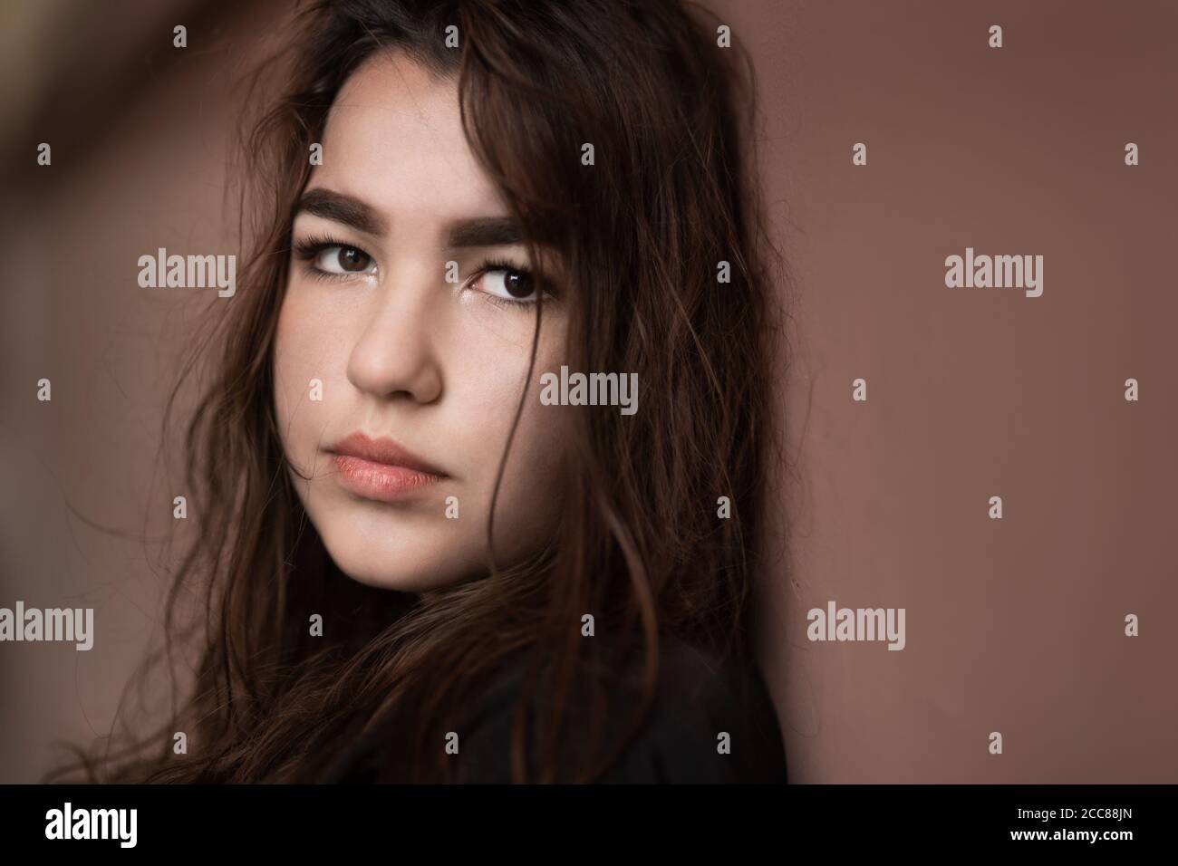 Young woman near wall and looks at the camera Stock Photo - Alamy