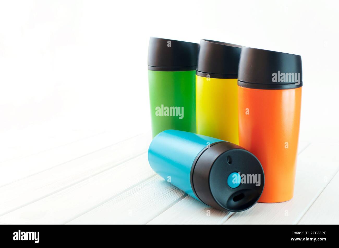 Four color thermos mugs on the white wooden table on white background ...