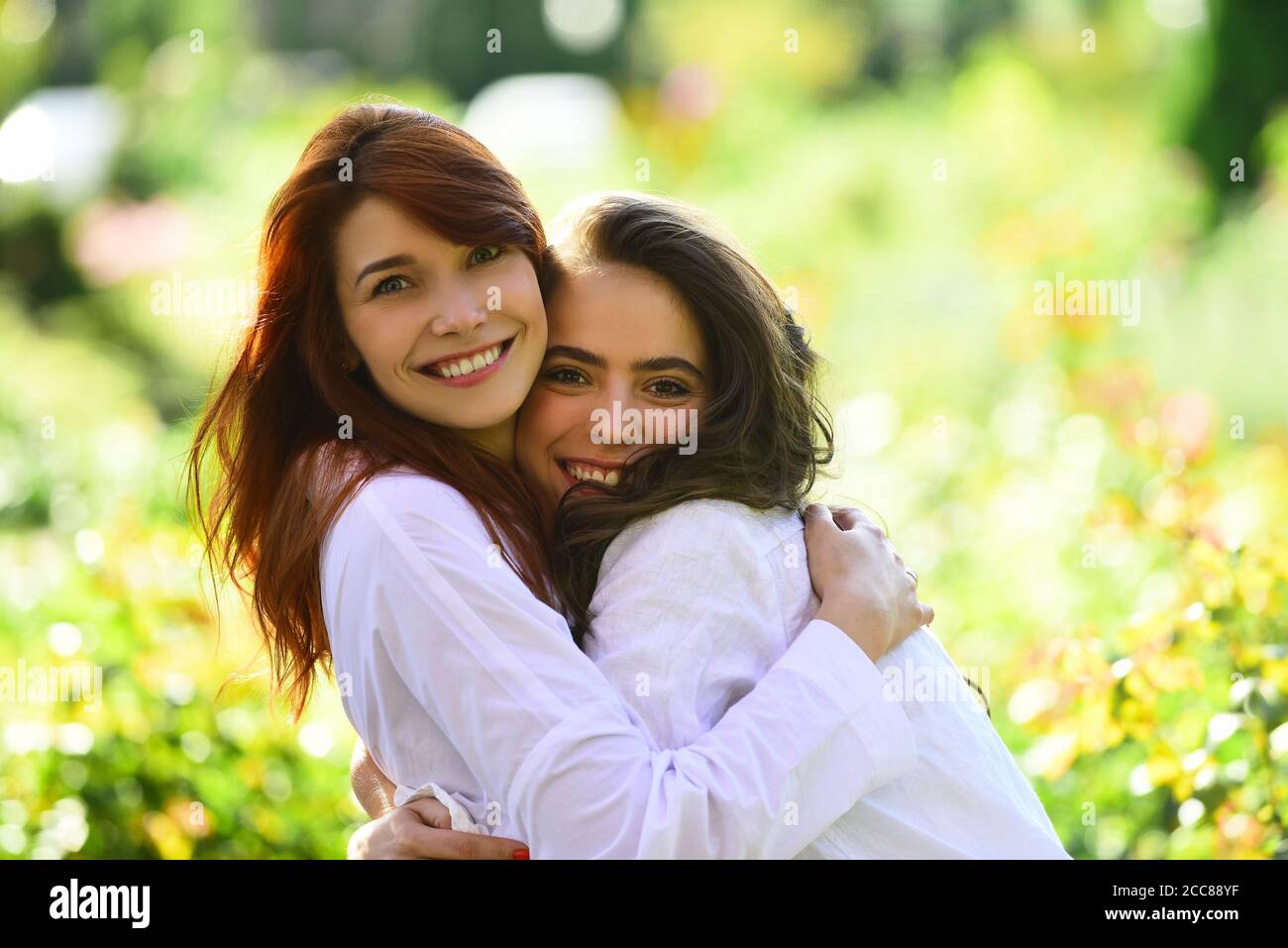 Girl friends laughing and hugging outdoors. Two women are hugging on ...