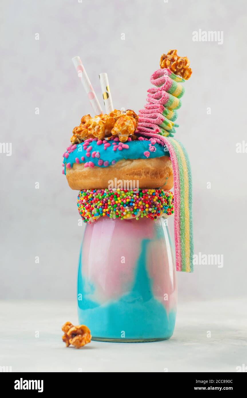 Freak shake topping with donut, popcorn and marmalade over grey ...