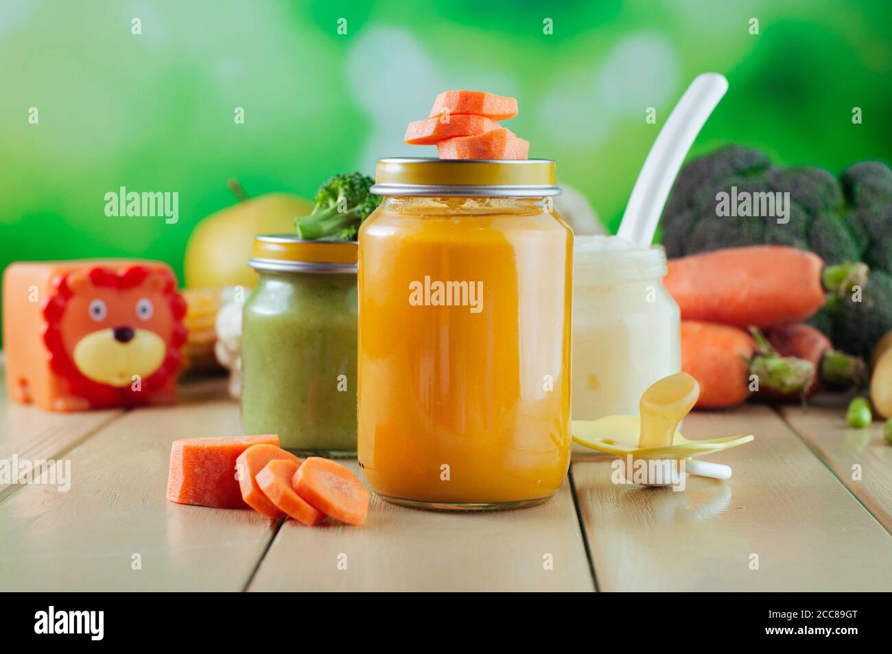 Jars with vegetable and fruit puree and juice near fresh vegetables ...