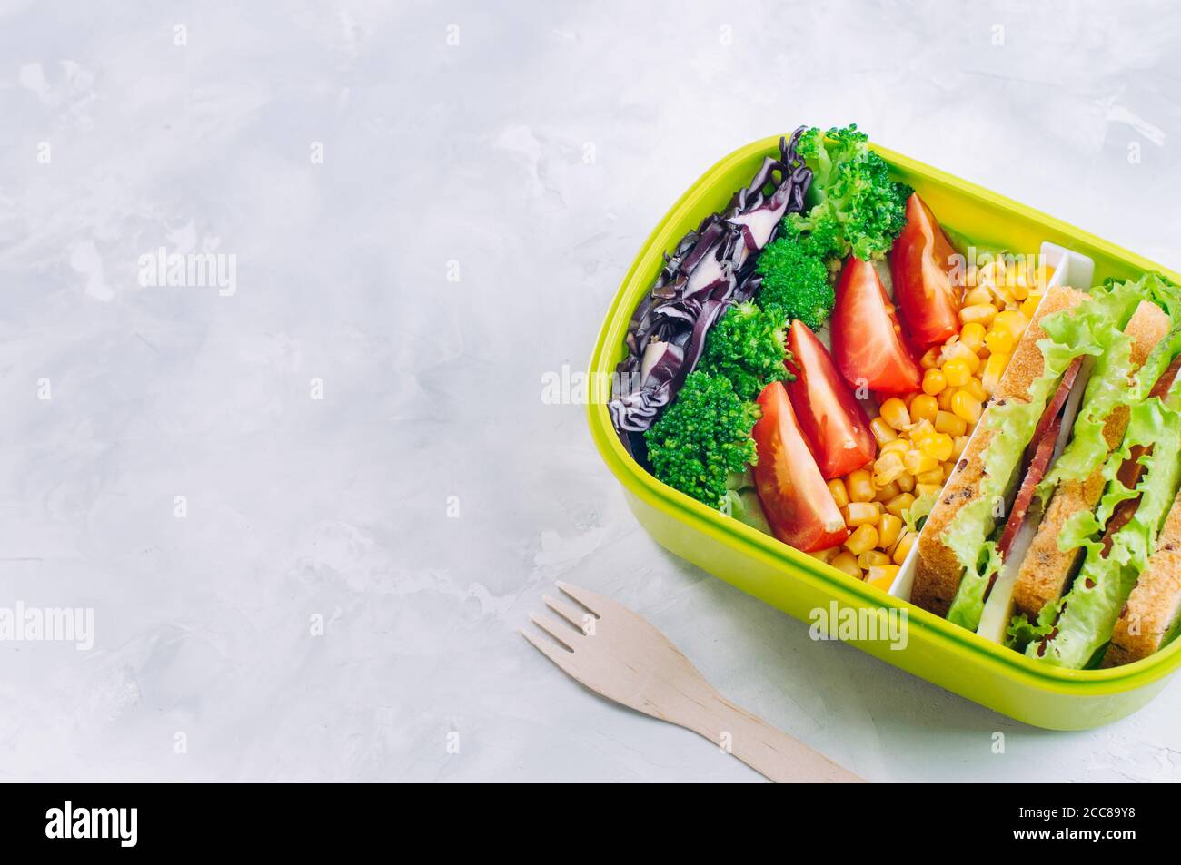 Lunch box filled with sandwich and vegetables on concrete background ...