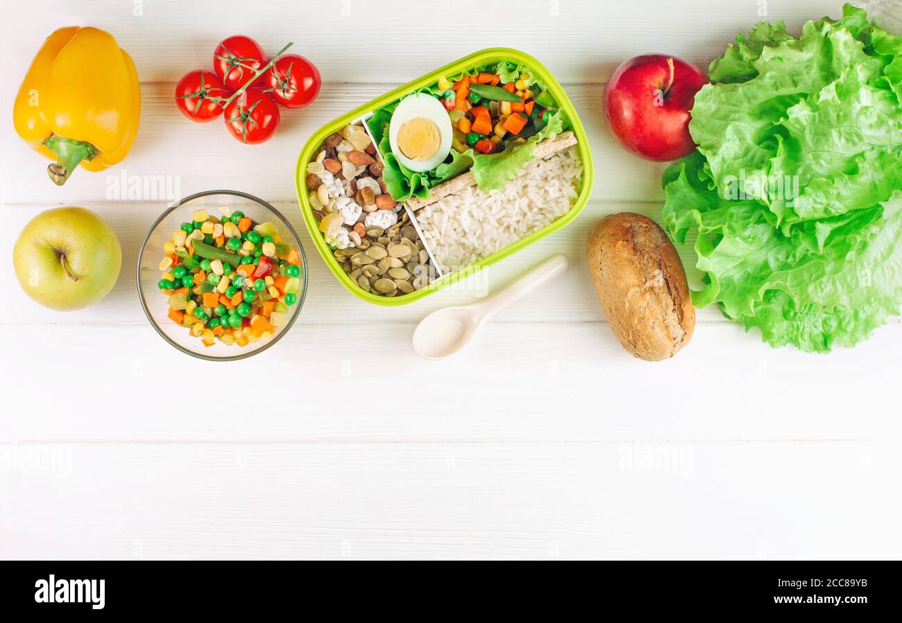 Lunch box filled with rice and mixed vegetables on white wooden ...