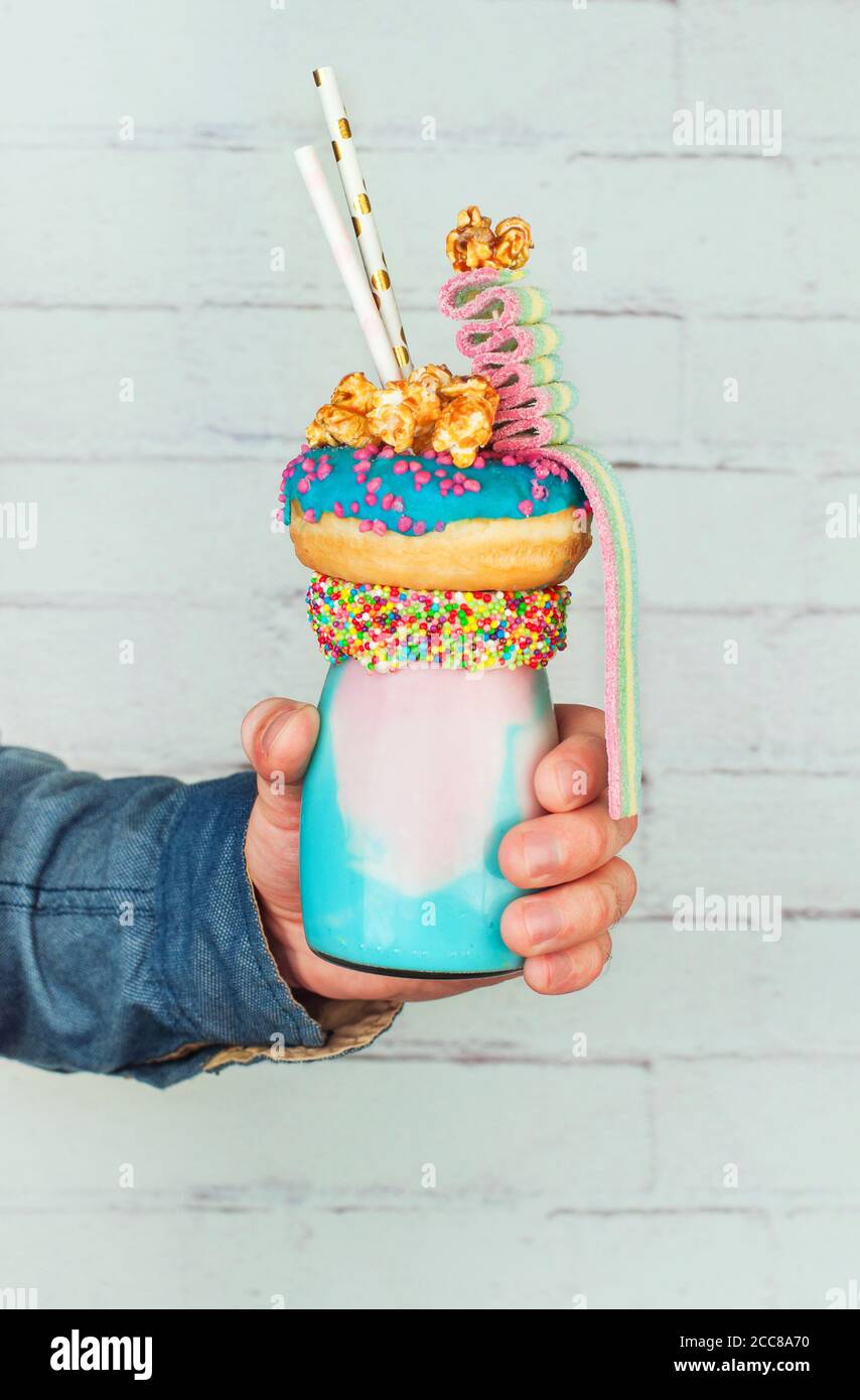 Males hand holding freak shake over grey brick background Stock Photo ...