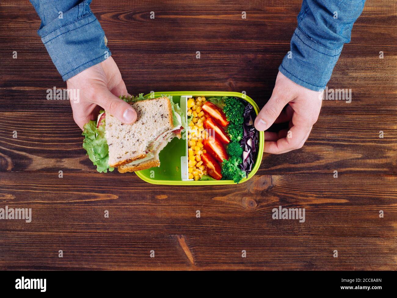 Males hands holding sandwich from his lunchbox filled with vegetables ...