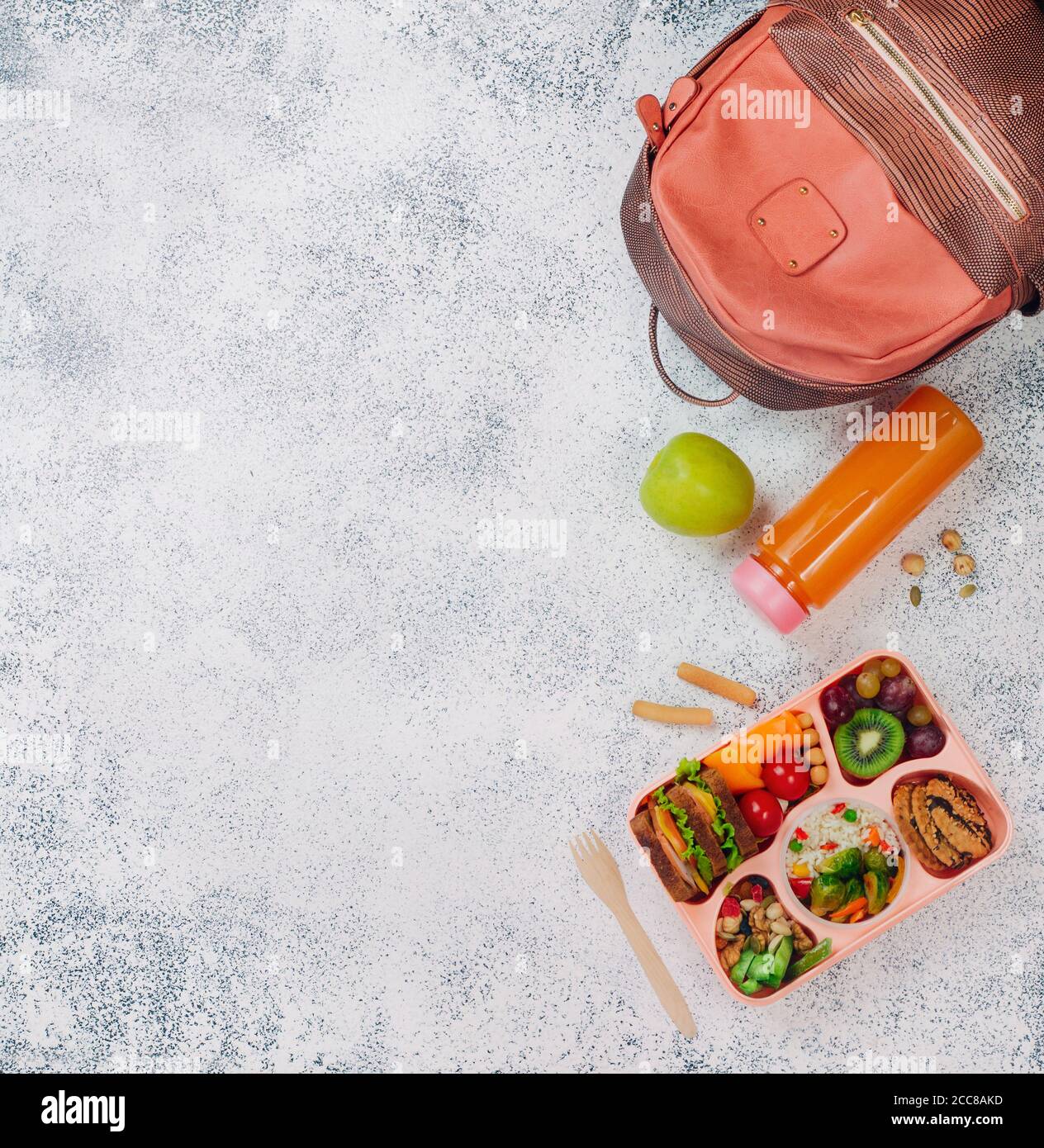 Open lunch box with healthy food on the grey background near backpack ...