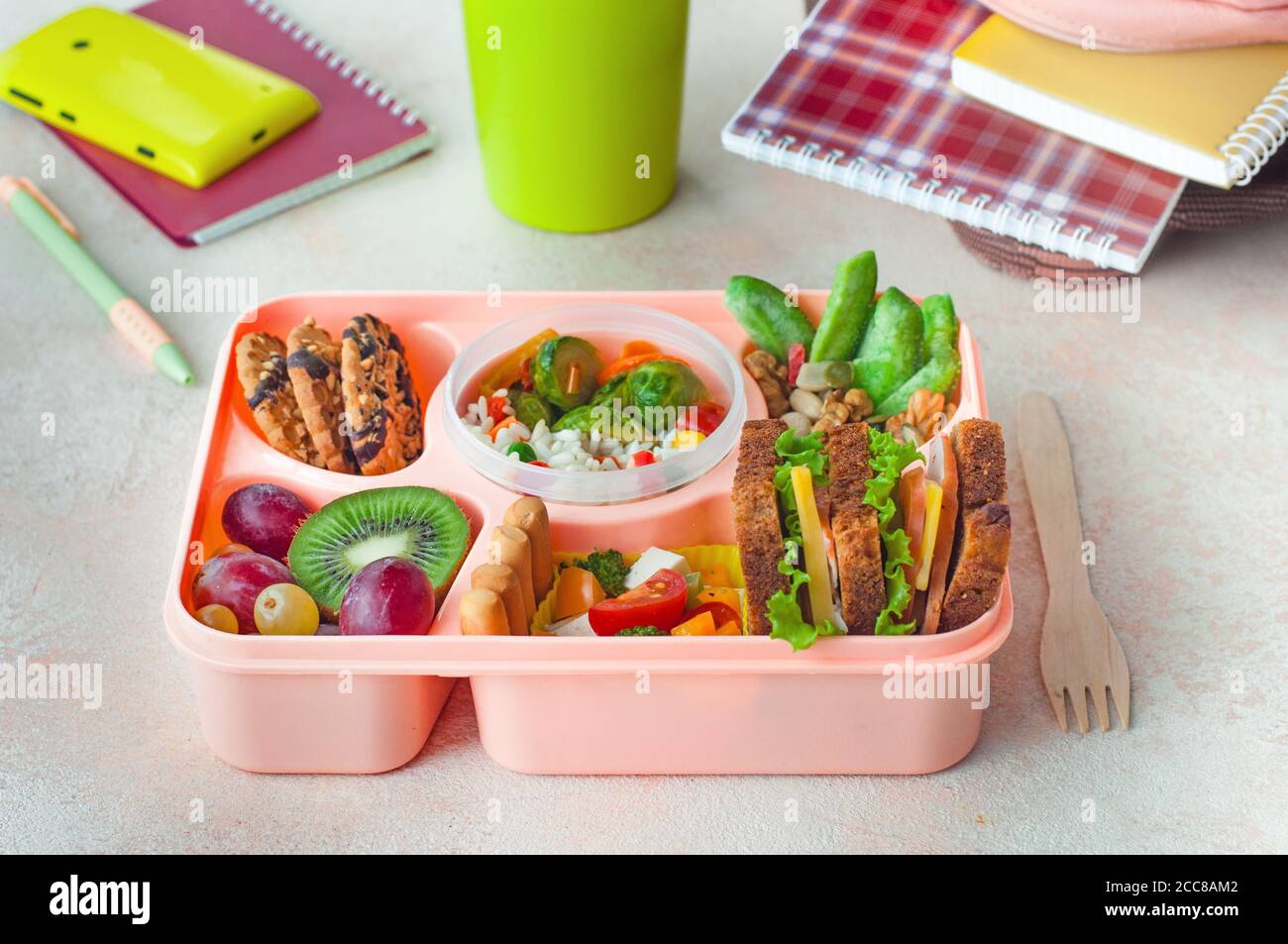 Open lunch box with healthy lunch on office table near backpack and mug ...
