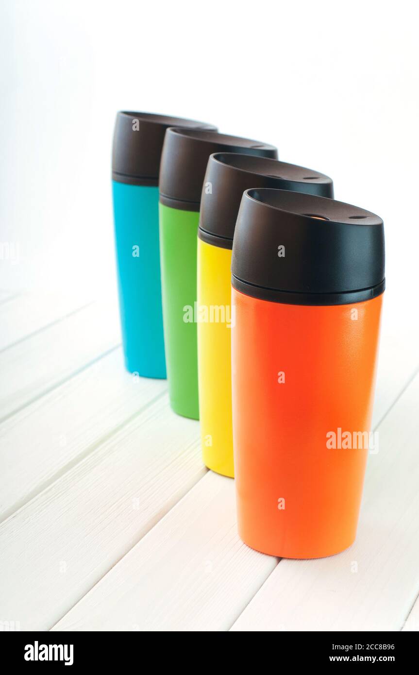 Series of color thermos mugs on the white wooden table Stock Photo - Alamy