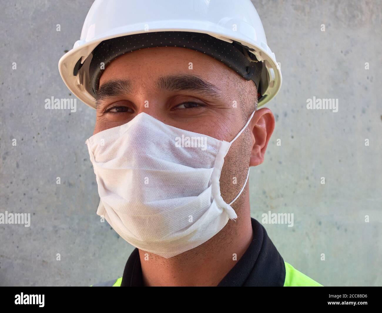 Civil engineer wears protective medical mask standing against concrete ...