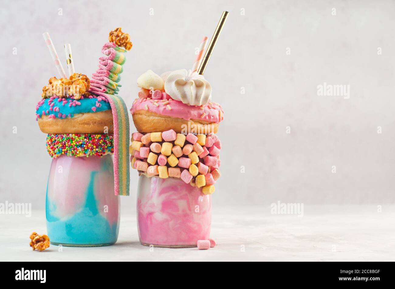 Two freak shakes topping with donut and meringues over grey background ...