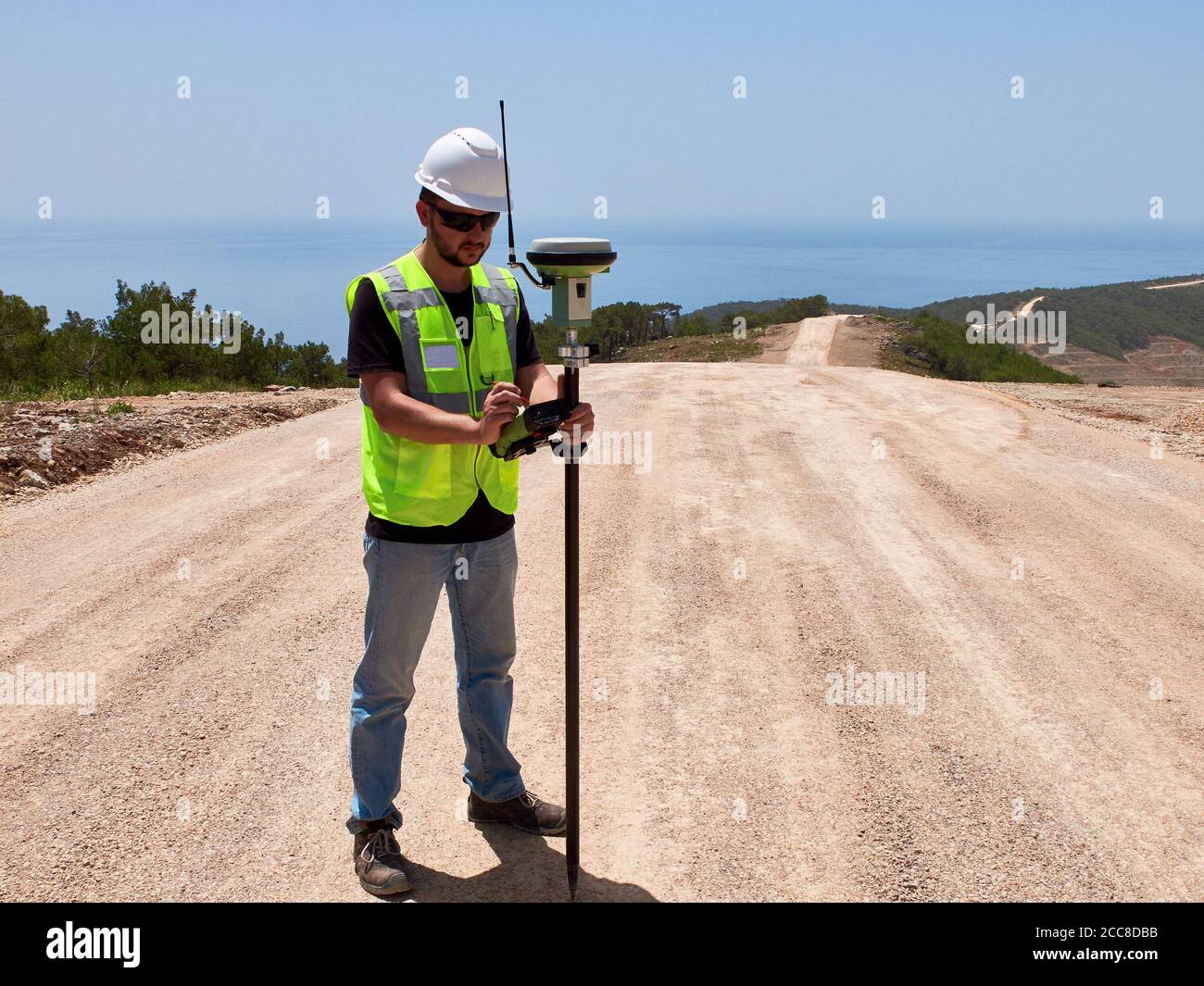 Geodetic engineer surveyor in white hard hat doing measurements with ...