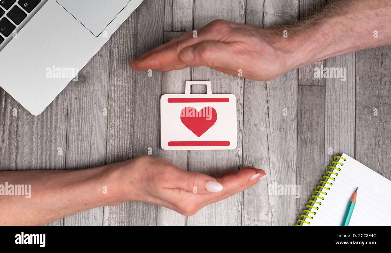 Hands protecting a paper medical briefcase; Symbol of health insurance ...
