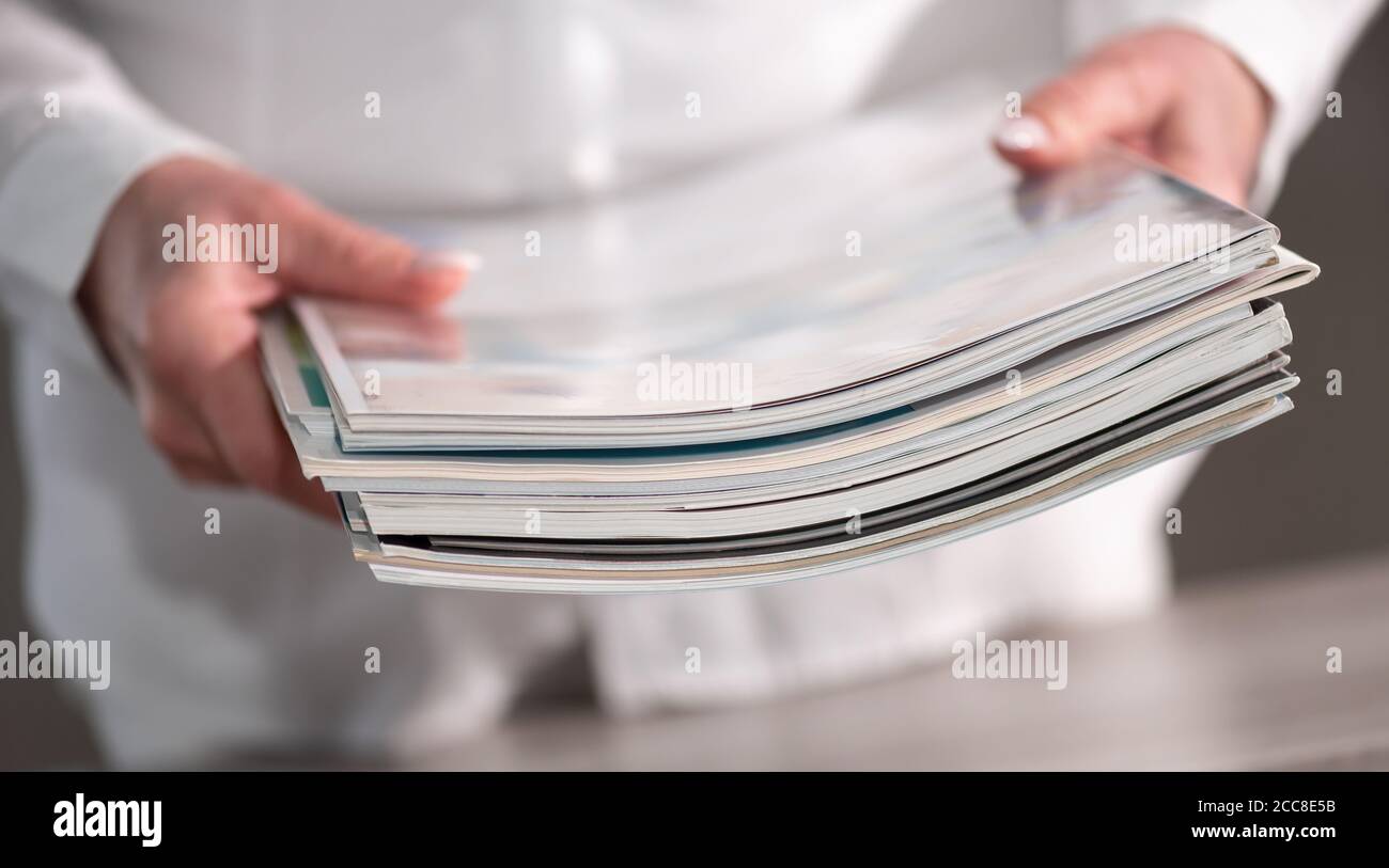 Female hands holding a stack of magazines Stock Photo - Alamy