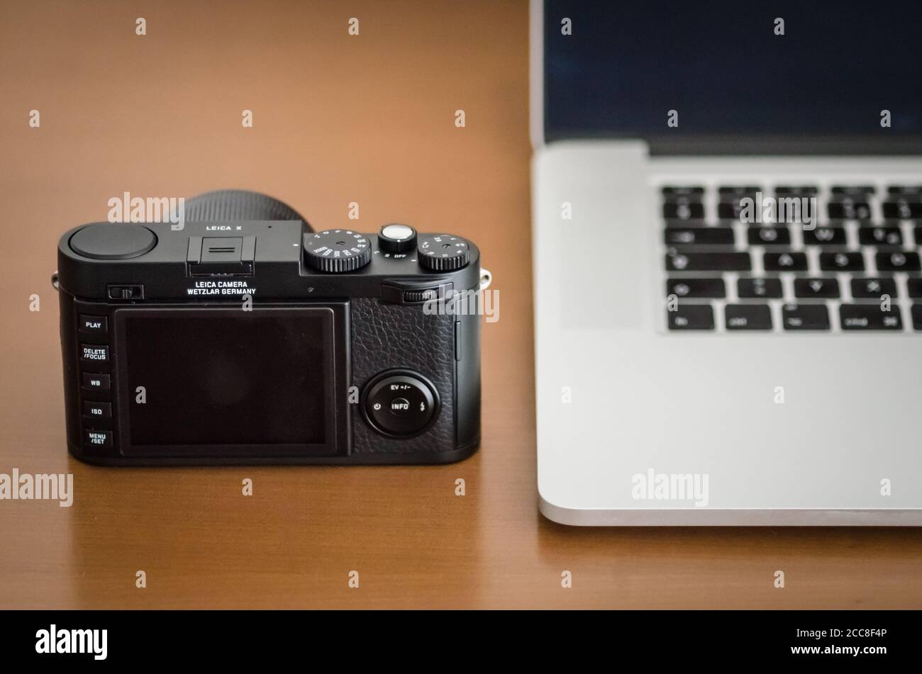 Leica X digital premium compact camera and MacBook Pro laptop on wooden ...