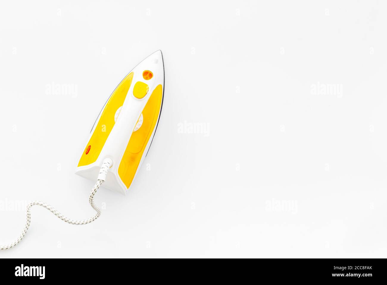 Yellow iron on ironing board. Top view, copy space Stock Photo - Alamy