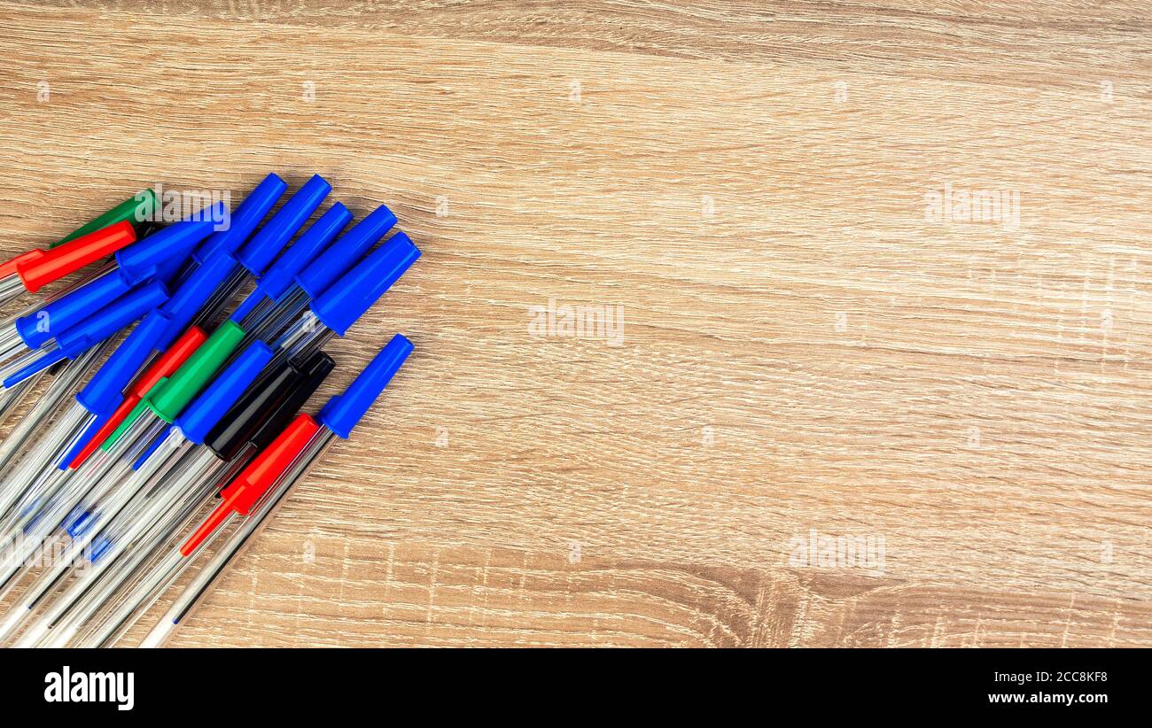 Pile of a lot multi colored plastic ballpoint pens on wooden table ...