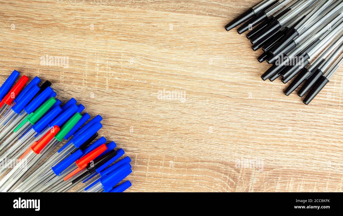 Pile of a lot multi colored plastic ballpoint pens on wooden table ...