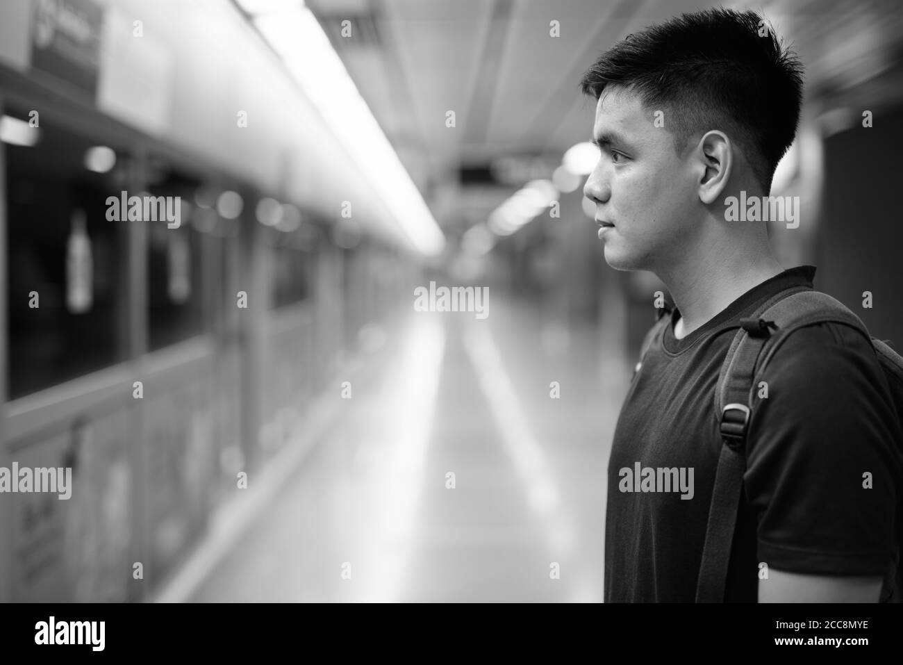 Young handsome Asian tourist man waiting for the train at the subway ...