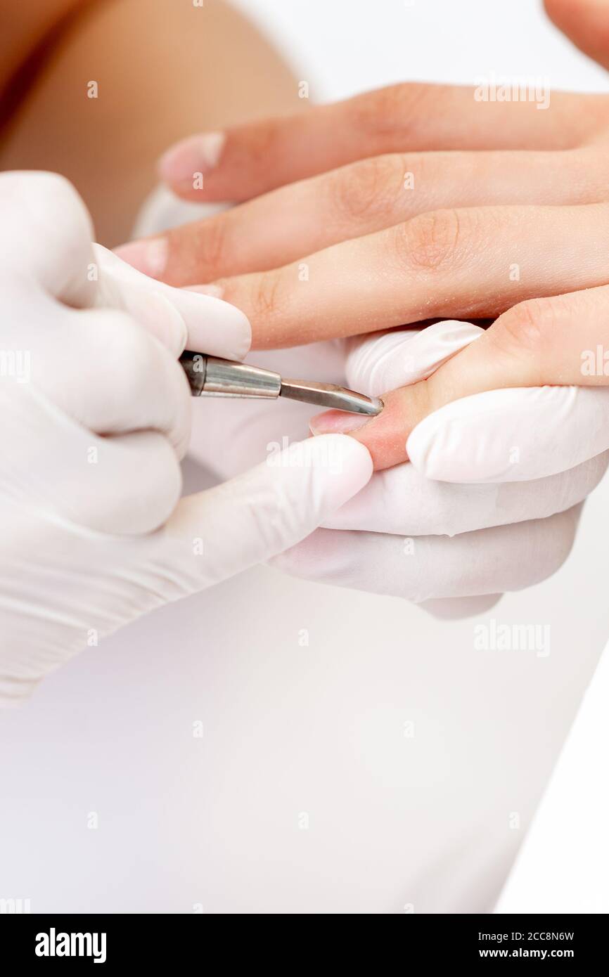 Hands of manicurist pushing cuticles on female's nails with manicure ...