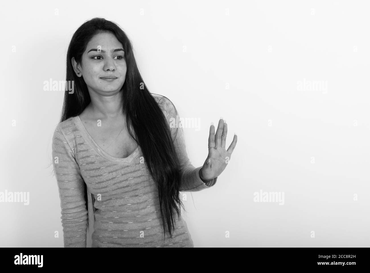 Studio shot of young Indian woman showing stop hand sign to the side ...