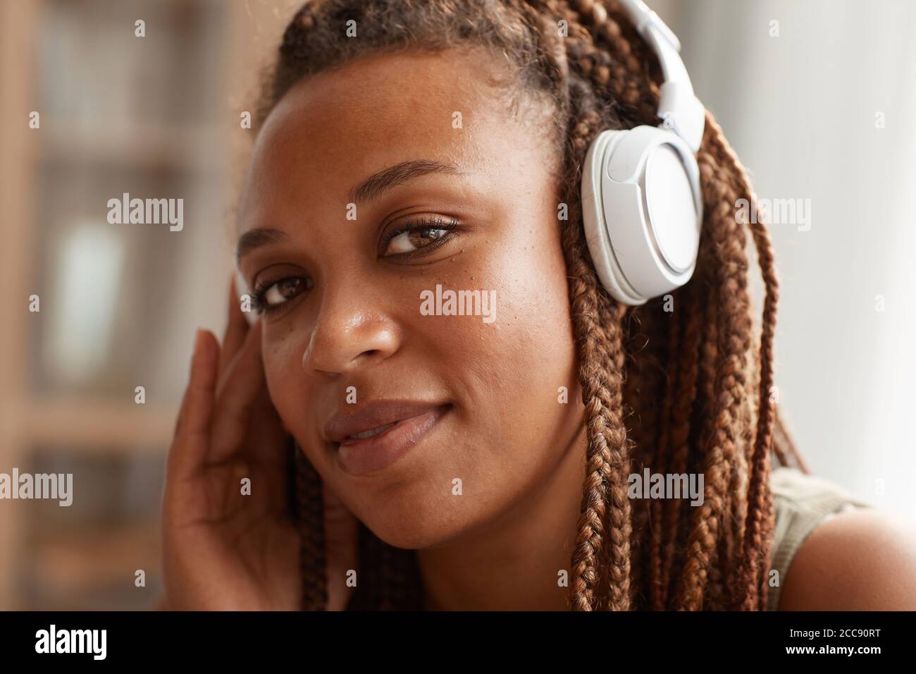 Close-up of African young woman with stylish hairstyle wearing wireless ...