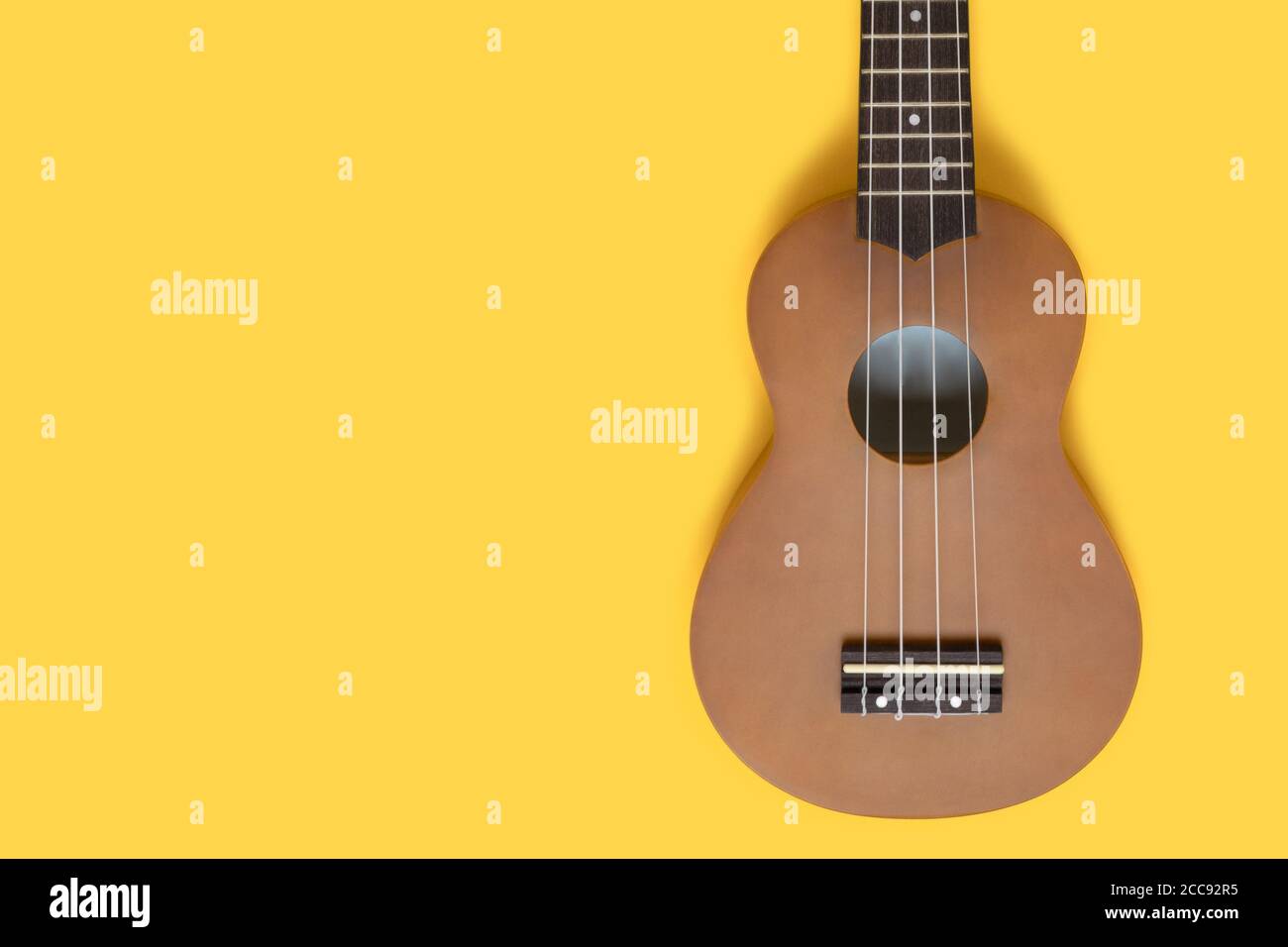 Ukulele on a bright yellow background. Musical equipment layout with ...