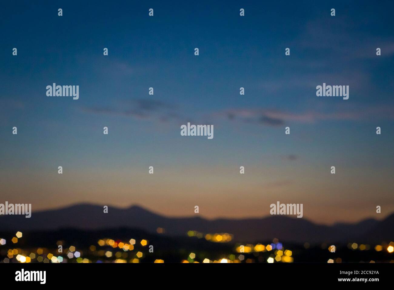 Blurred, out of focus landscape with blue fading sunset sky and city ...