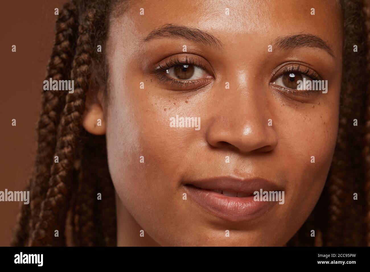 Close-up of face of African young woman with perfect skin looking at ...