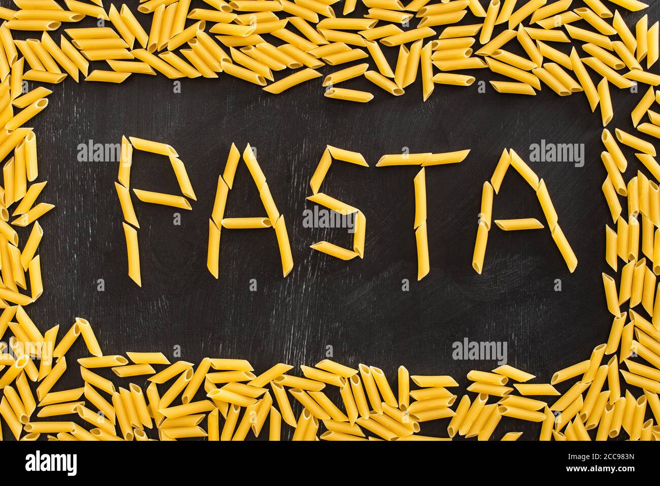 top view of pasta word made of raw penne on black background Stock ...
